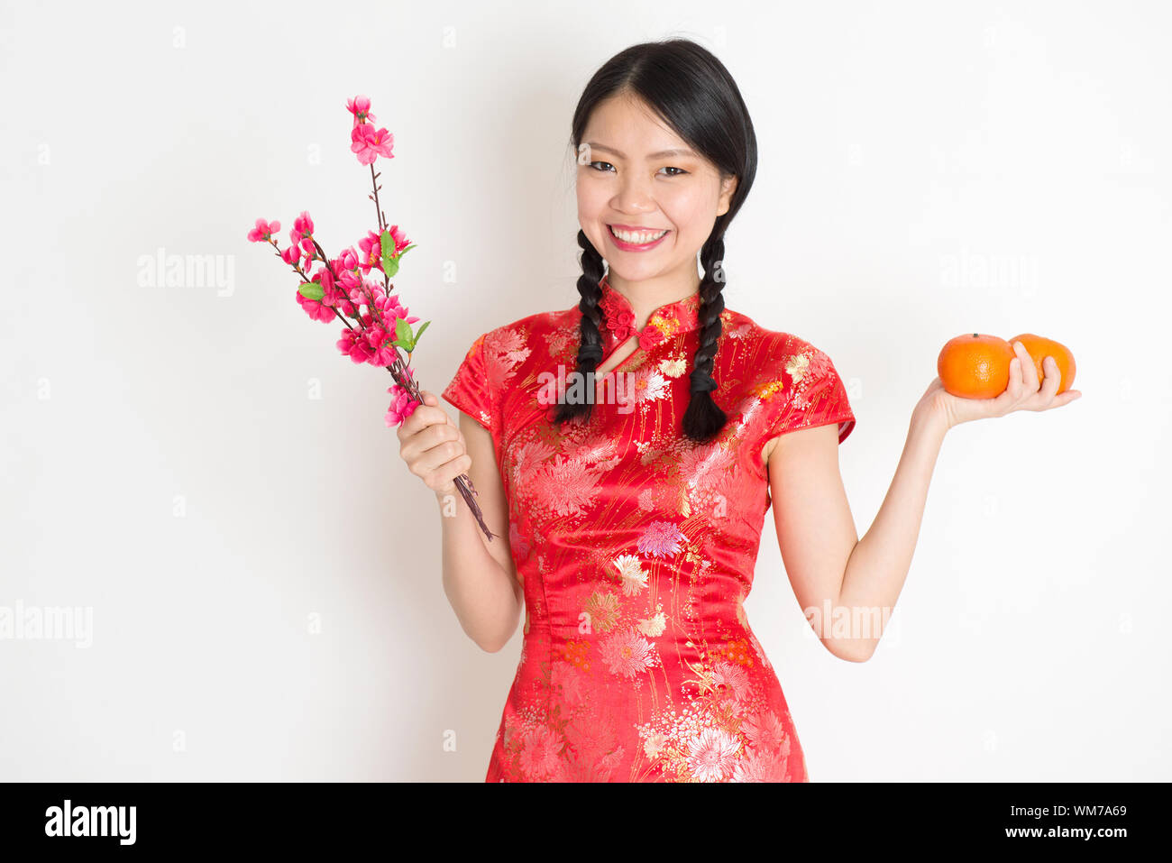 Portrait of Asian Chinese girl hands holding tangerine orange and plum ...