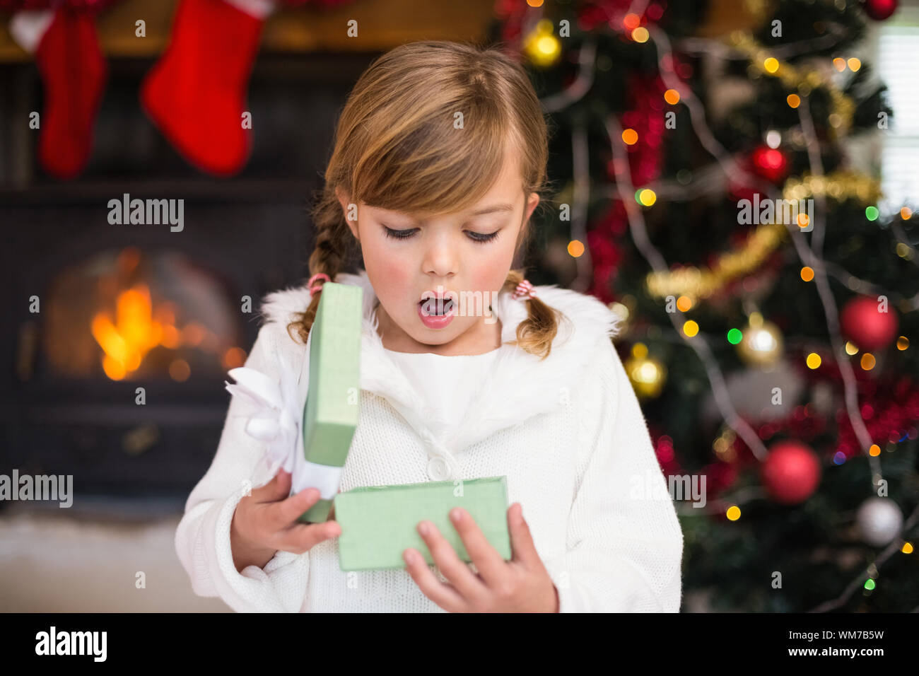 Shocked little girl opening a gift at home in the living room Stock ...