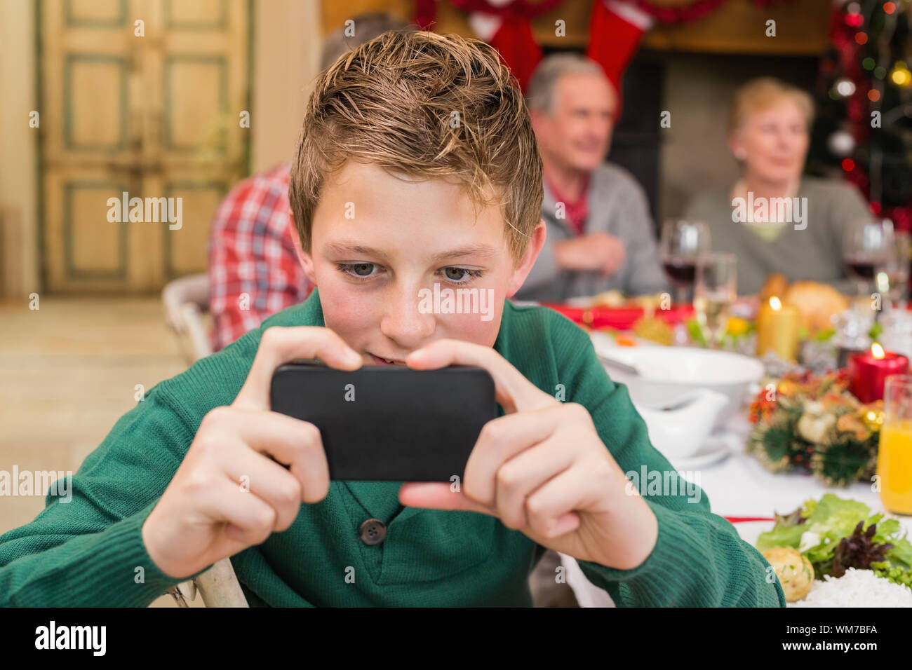 Young boy holding smartphone during christmas dinner at home in the ...