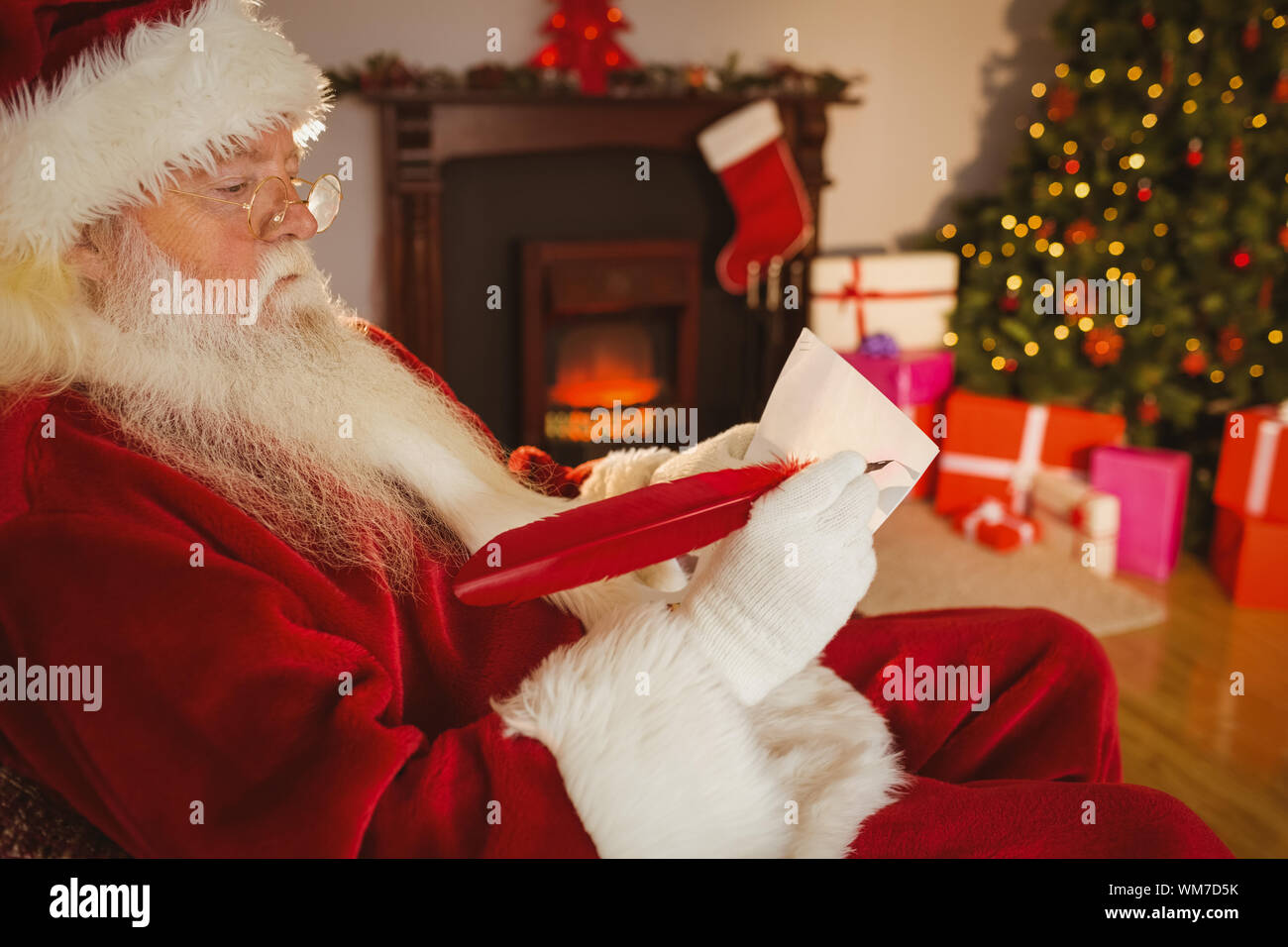 Santa claus writing list on scroll at home in the living room Stock ...