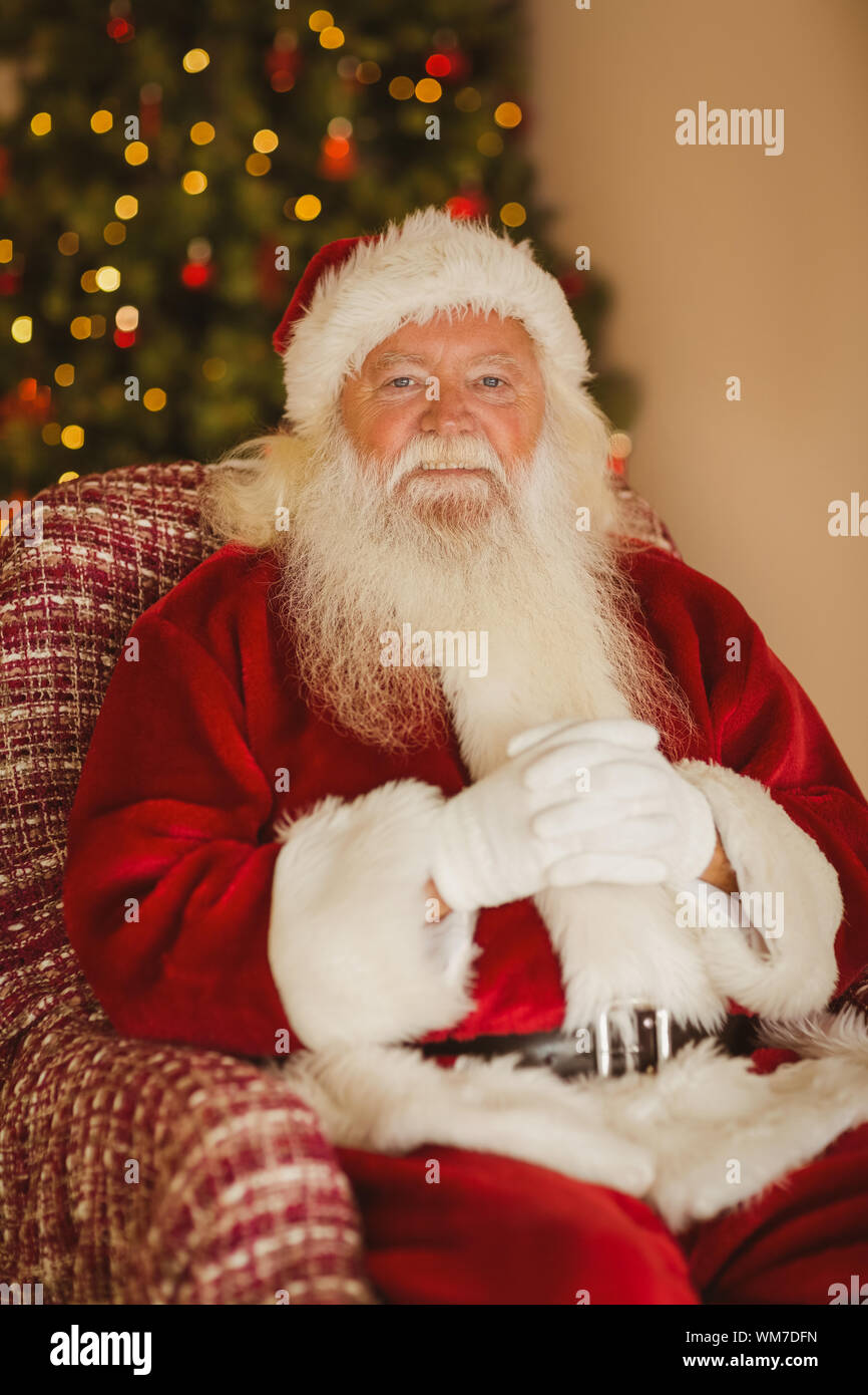 Happy santa relaxing on the armchair at home in the living room Stock ...