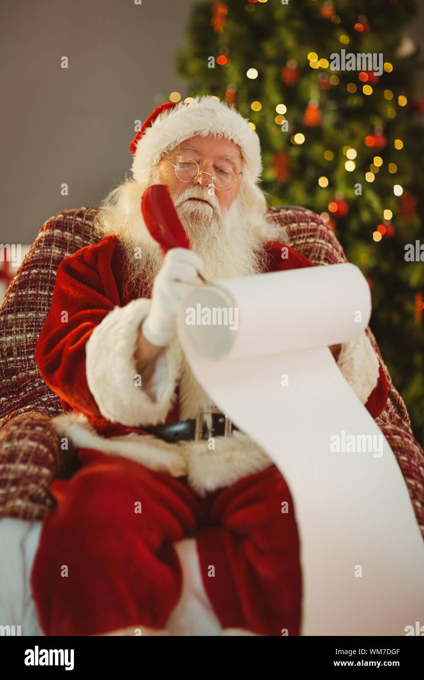 Concentrated santa writing his list on a scroll at home in the living ...
