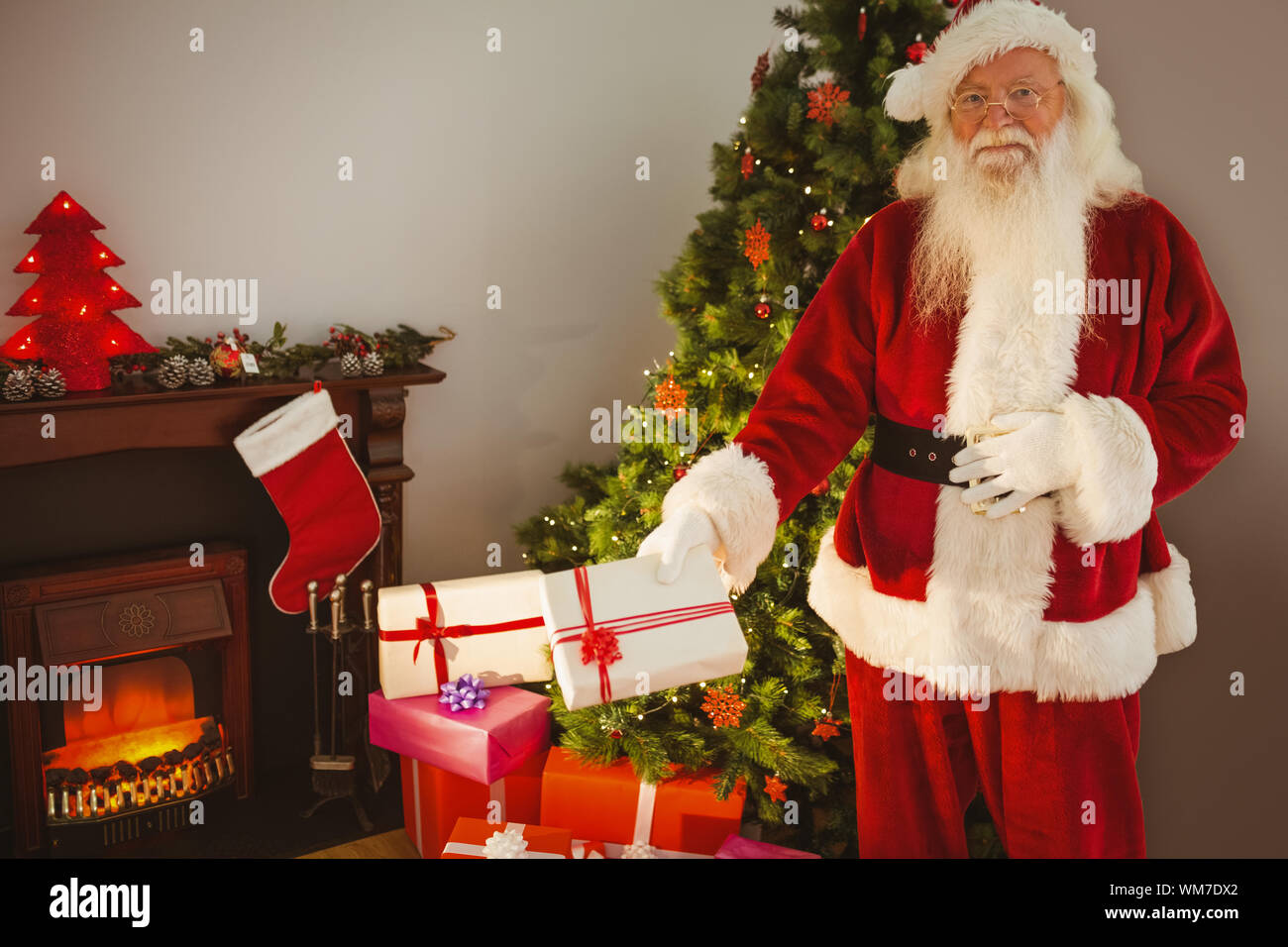Joyful santa delivering gifts at christmas eve at home in the living ...