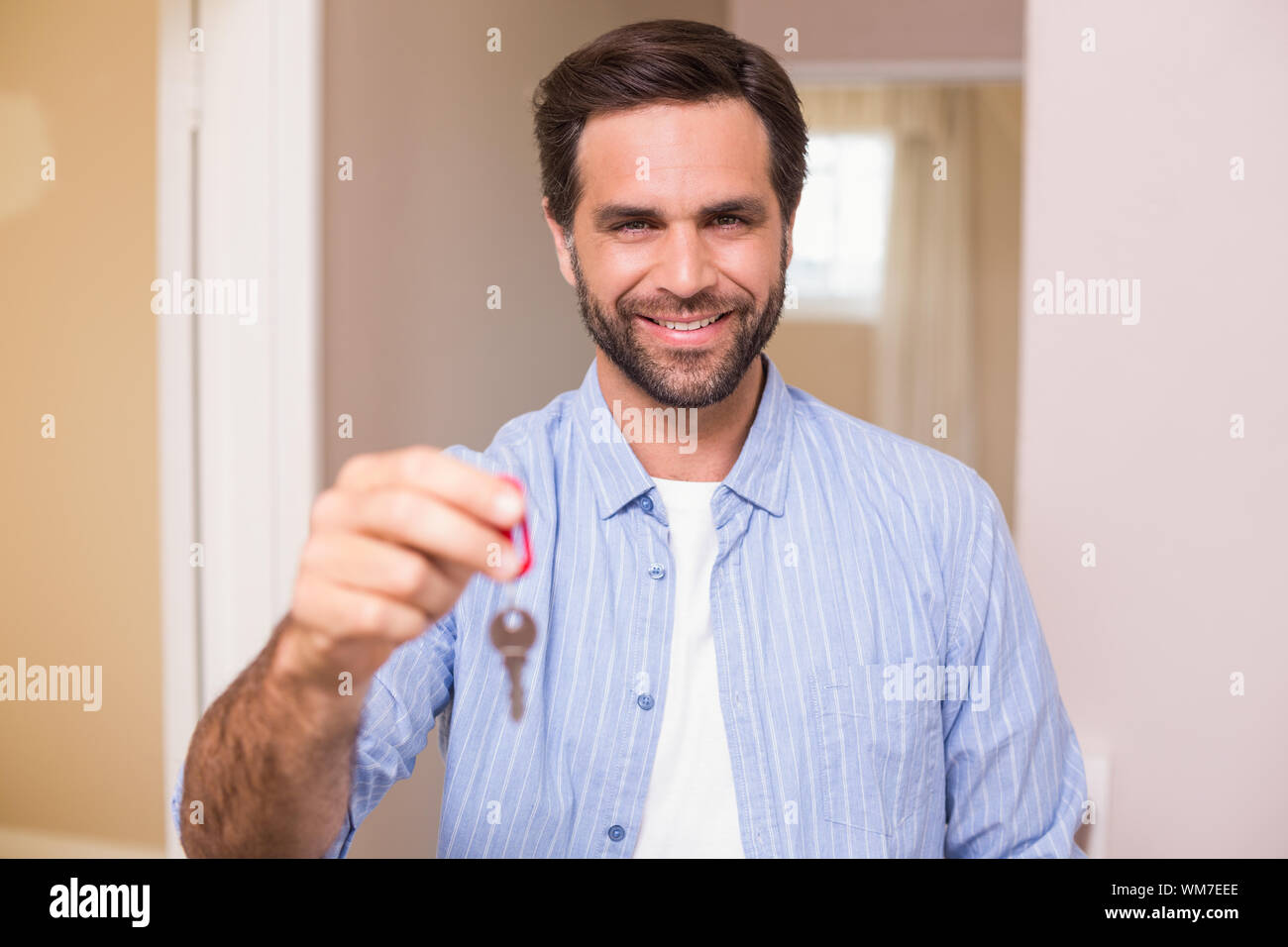 Casual man showing his house key in his new home Stock Photo - Alamy