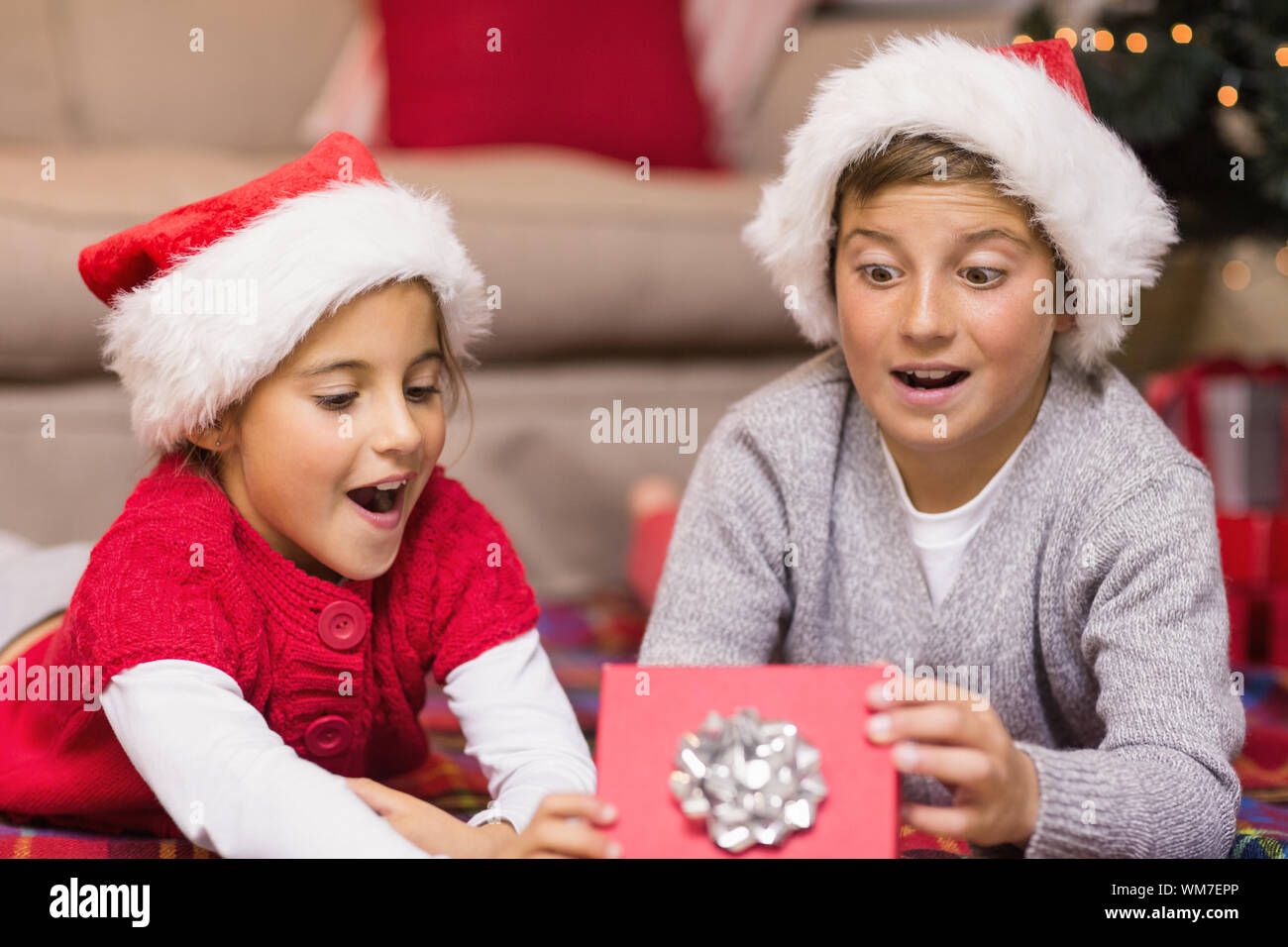 Shocked brother and sister opening a gift at home in the living room ...
