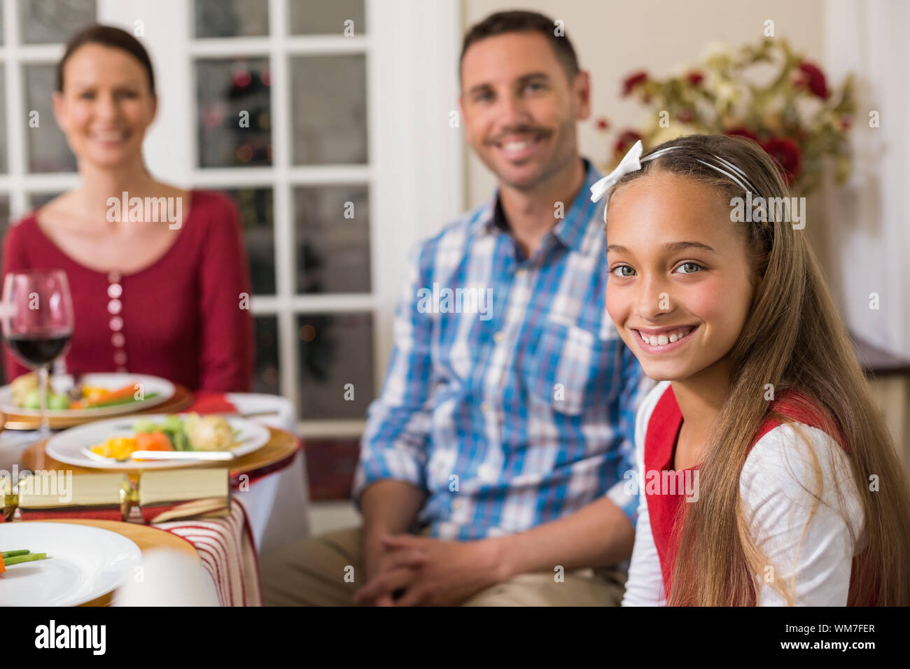 Portrait of cute girl with her parents behind at home in the living ...