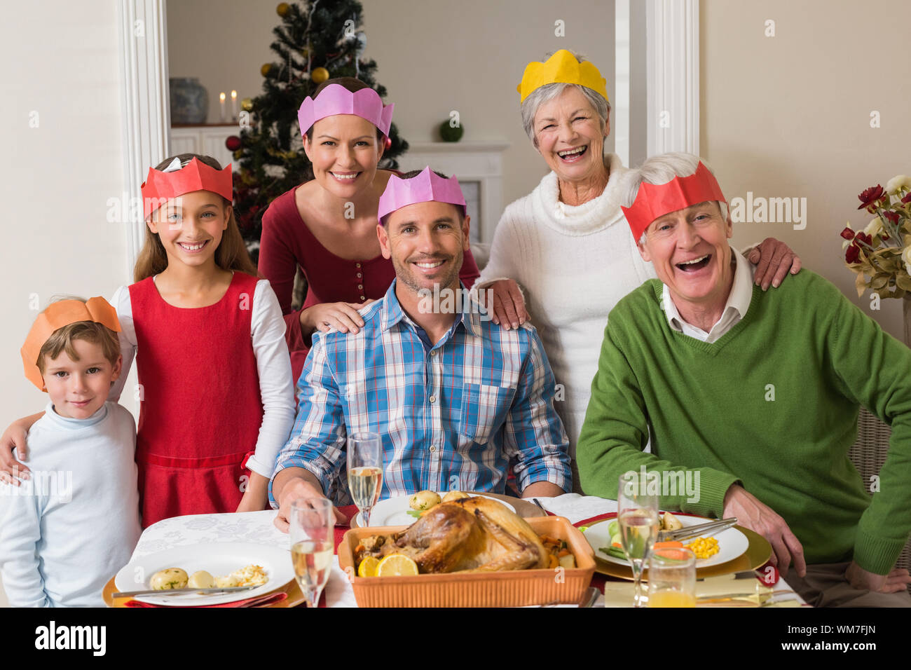 Happy extended family in party hat at dinner table at home in the ...