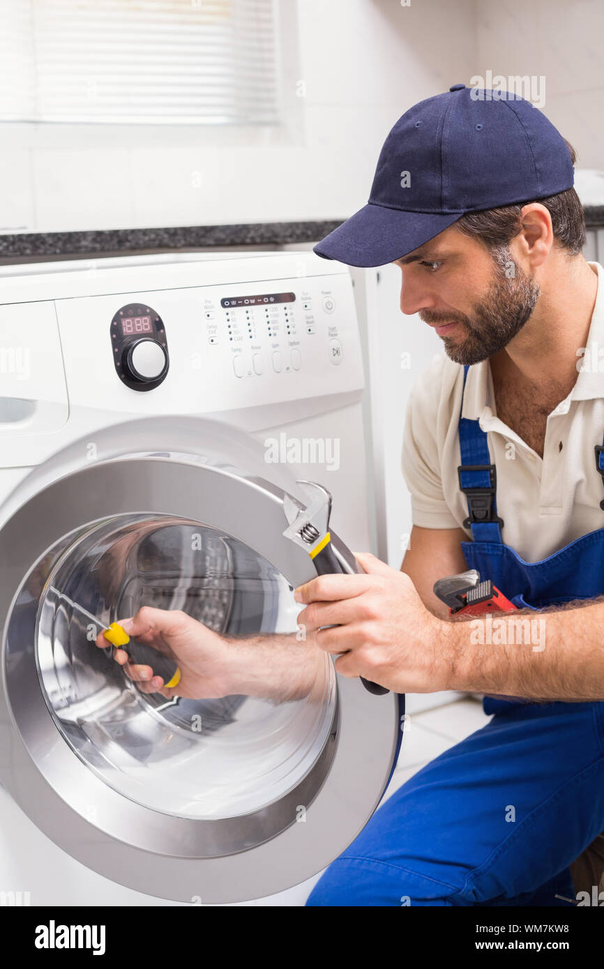 Handyman fixing a washing machine in the kitchen Stock Photo - Alamy