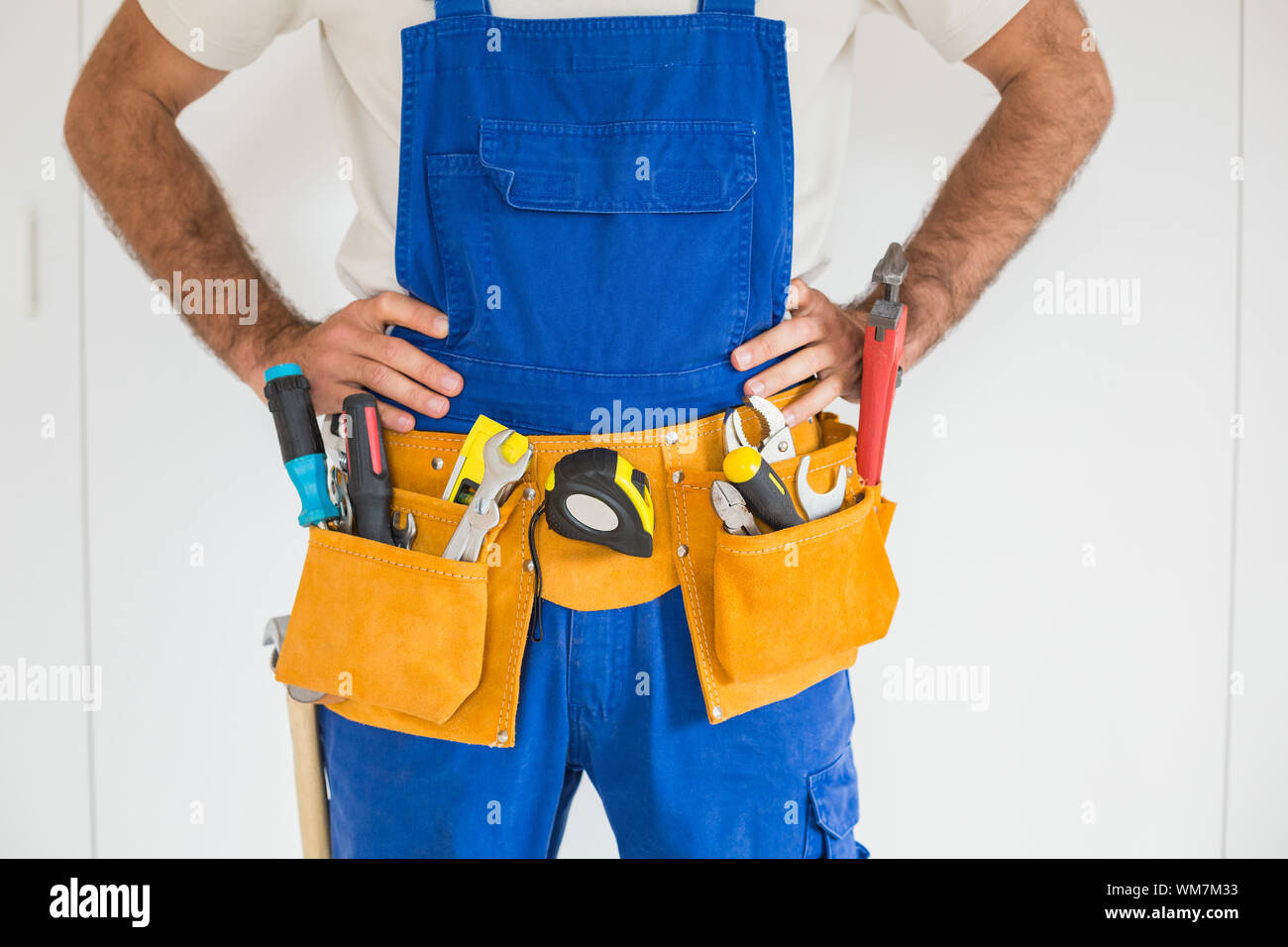 Handyman standing in tool belt in a new house Stock Photo - Alamy