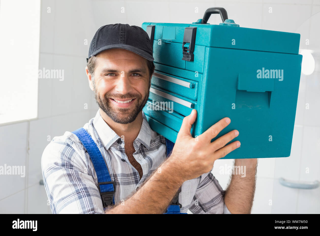 Plumber holding toolbox on shoulder in the bathroom Stock Photo - Alamy