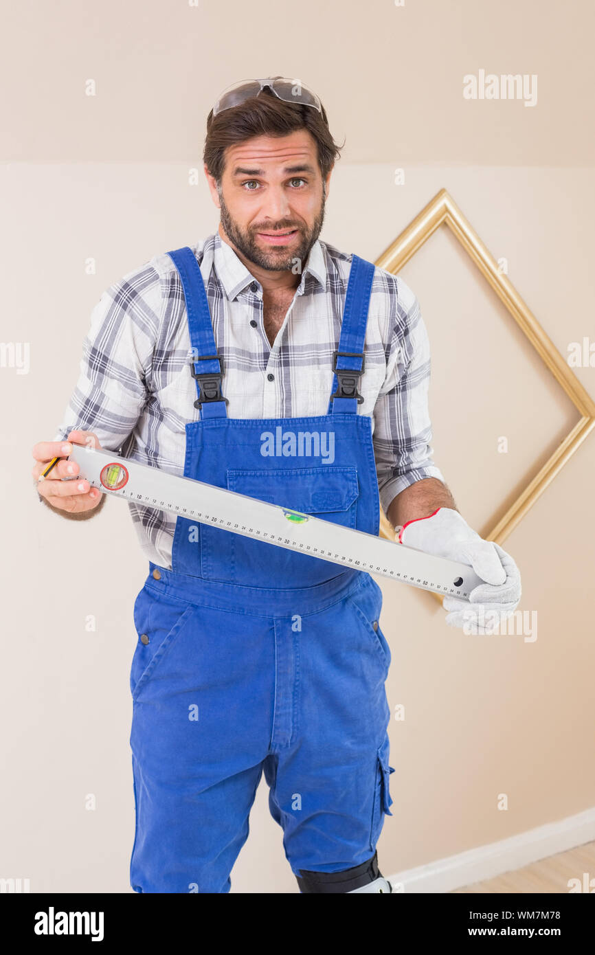 Confused construction worker holding spirit level in a new house Stock ...