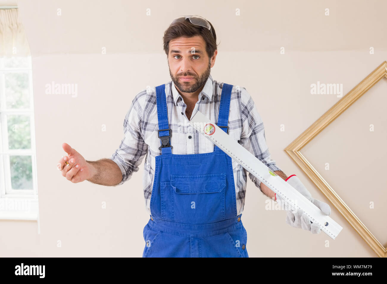 Confused construction worker holding spirit level in a new house Stock ...