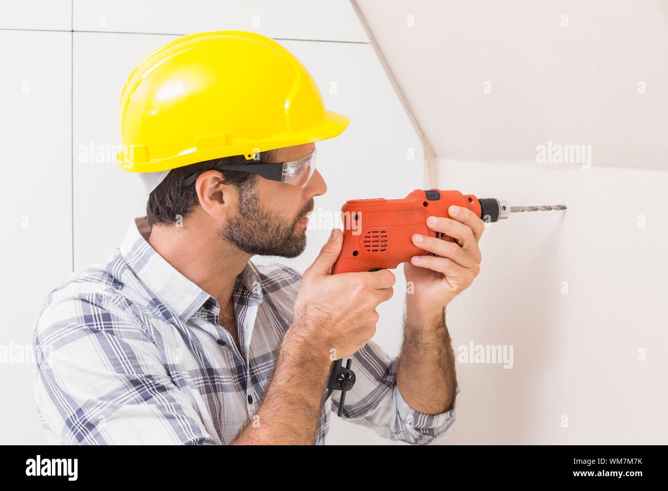 Construction worker drilling hole in wall in a new house Stock Photo ...