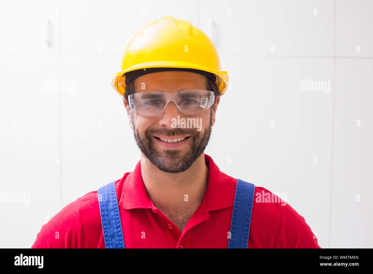 Construction worker smiling at camera in a new house Stock Photo - Alamy