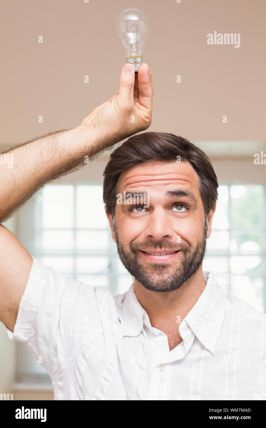 Man holding light bulb over his head at home in the living room Stock ...
