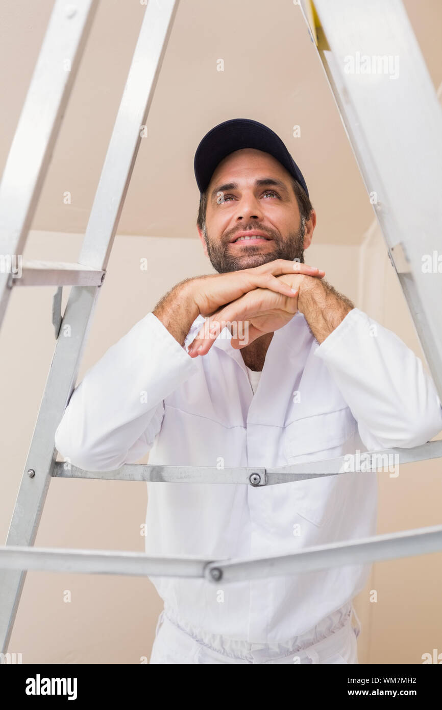 Painter smiling leaning on ladder in a new house Stock Photo - Alamy