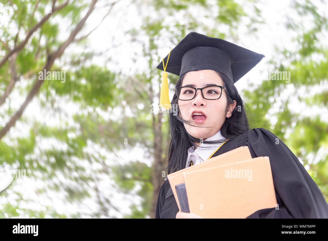 Young crazy asian woman graduating holding diploma with pride and funny ...