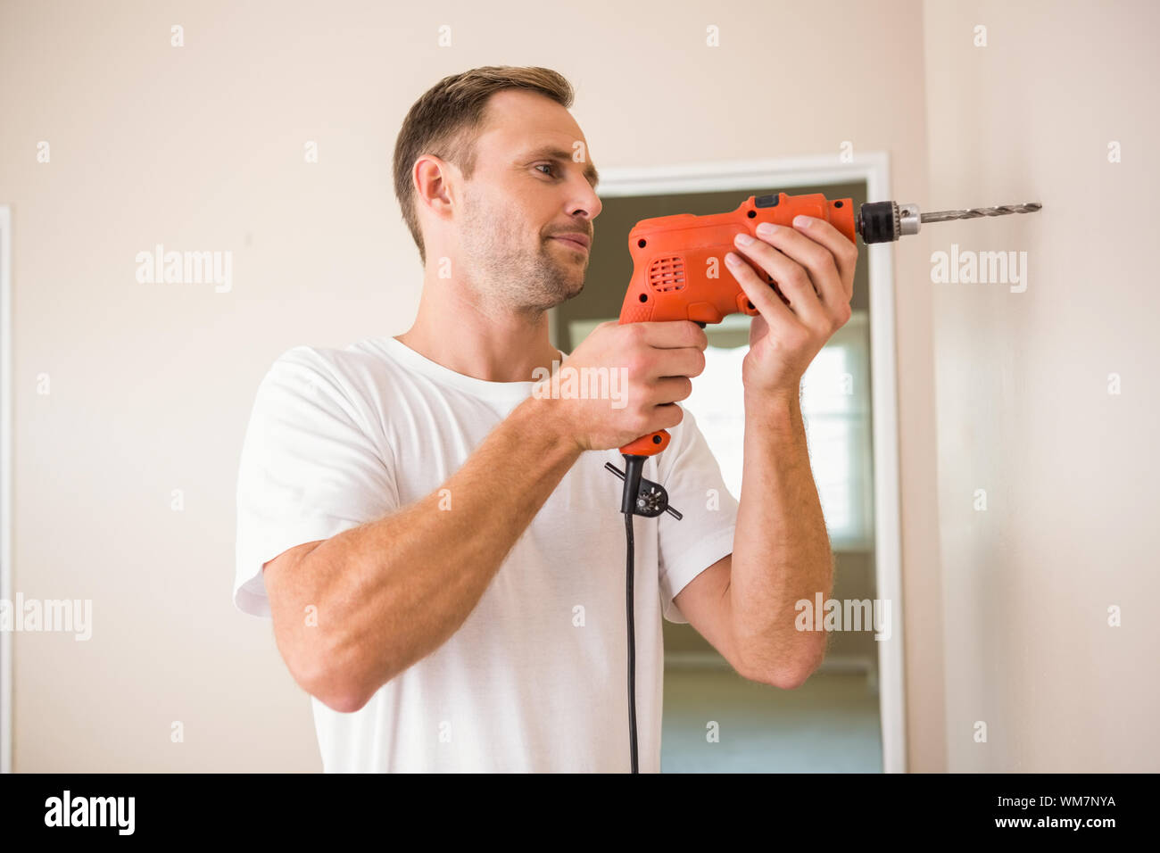 Construction worker drilling hole in wall in a new house Stock Photo ...