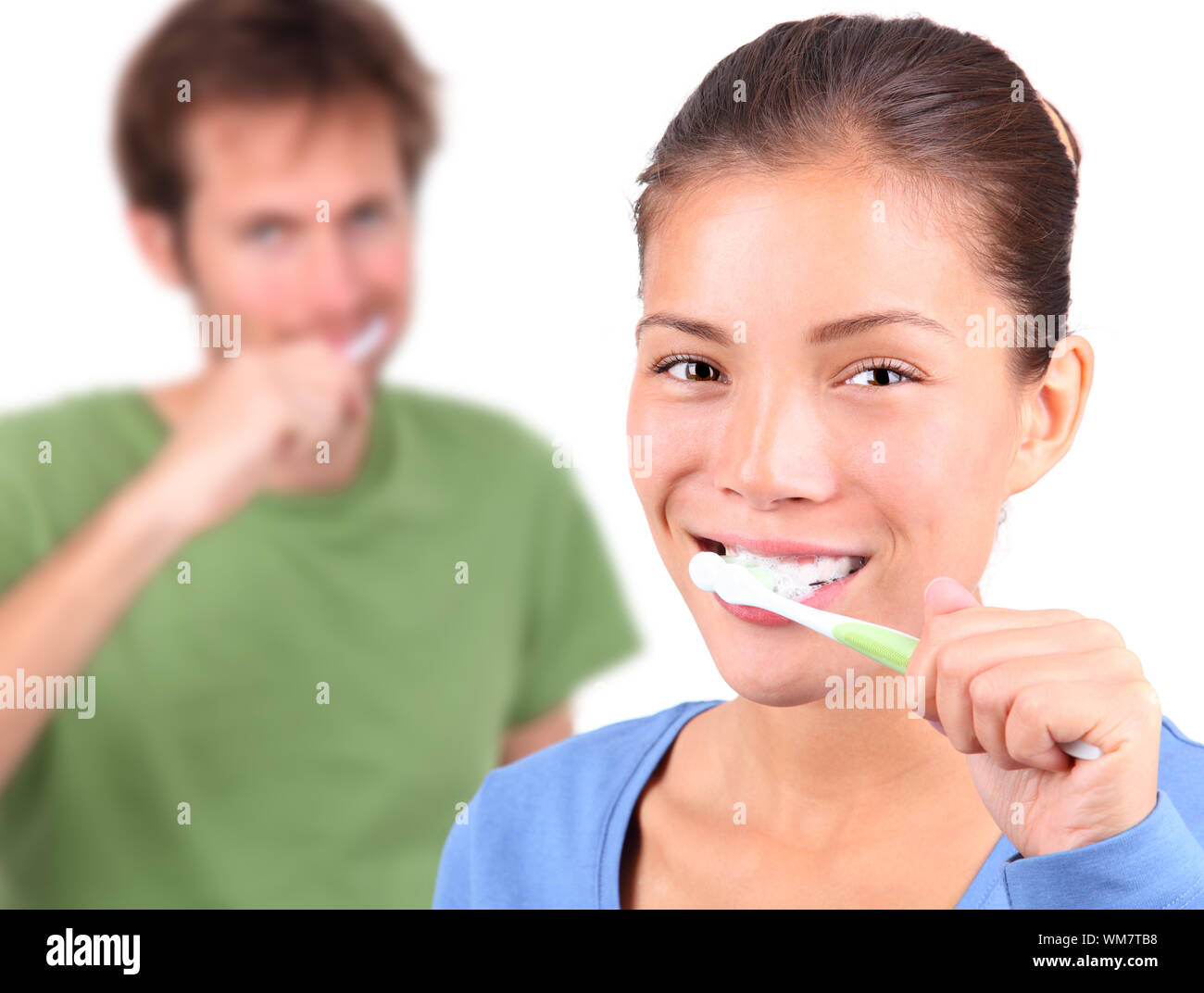 Young mixed race couple brushing teeth together on white background ...