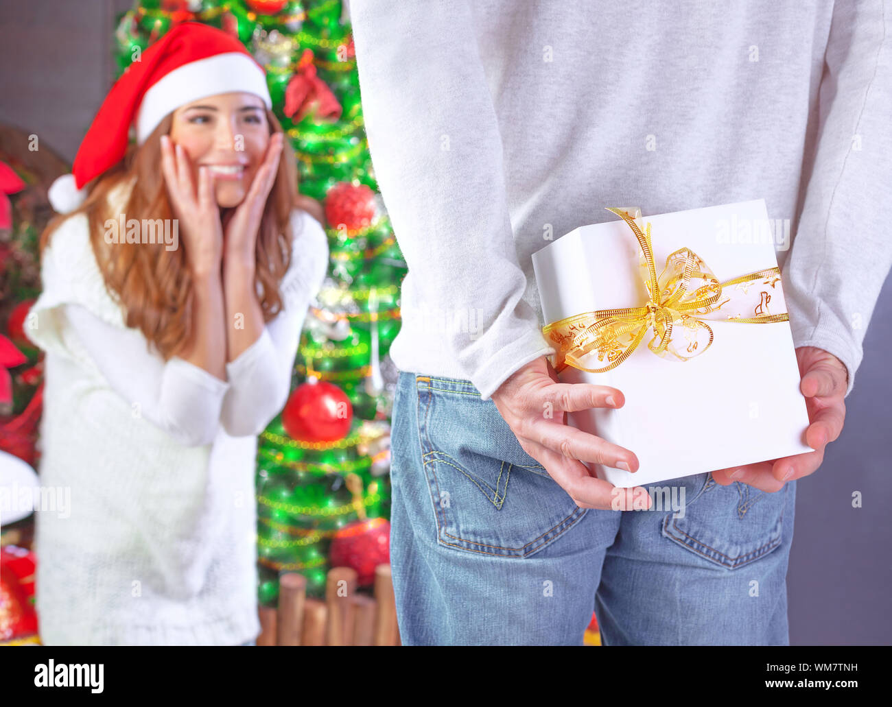 Pretty cheerful woman excited to see her husband hide gift behind back ...