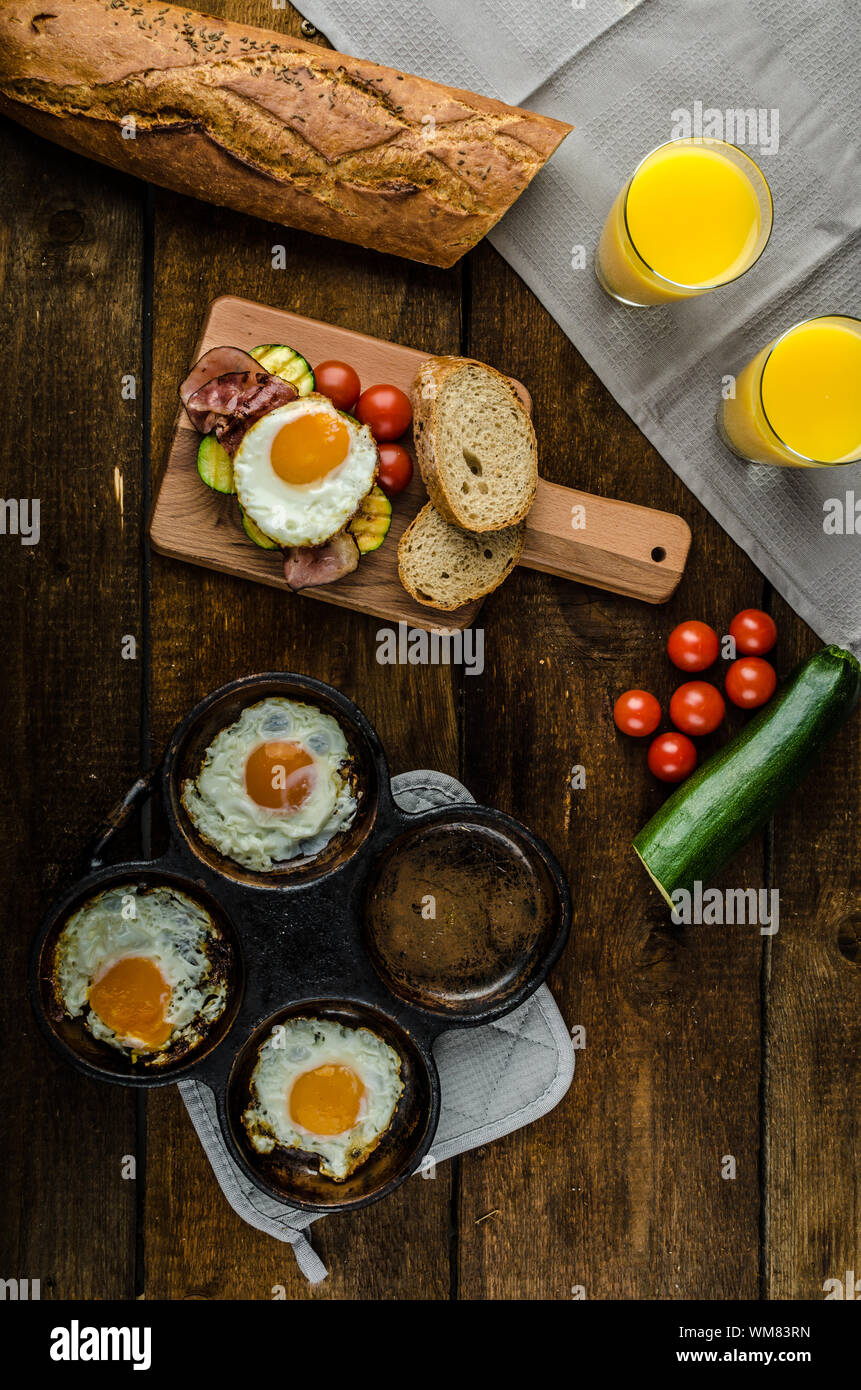 Rustic breakfast, fresh eggs baked in griddles, bacon, vegetables ...