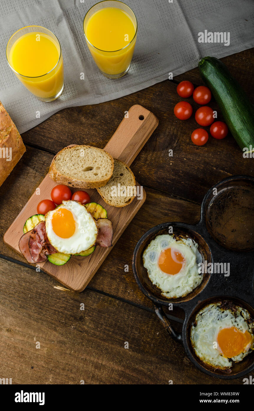 Rustic breakfast, fresh eggs baked in griddles, bacon, vegetables ...