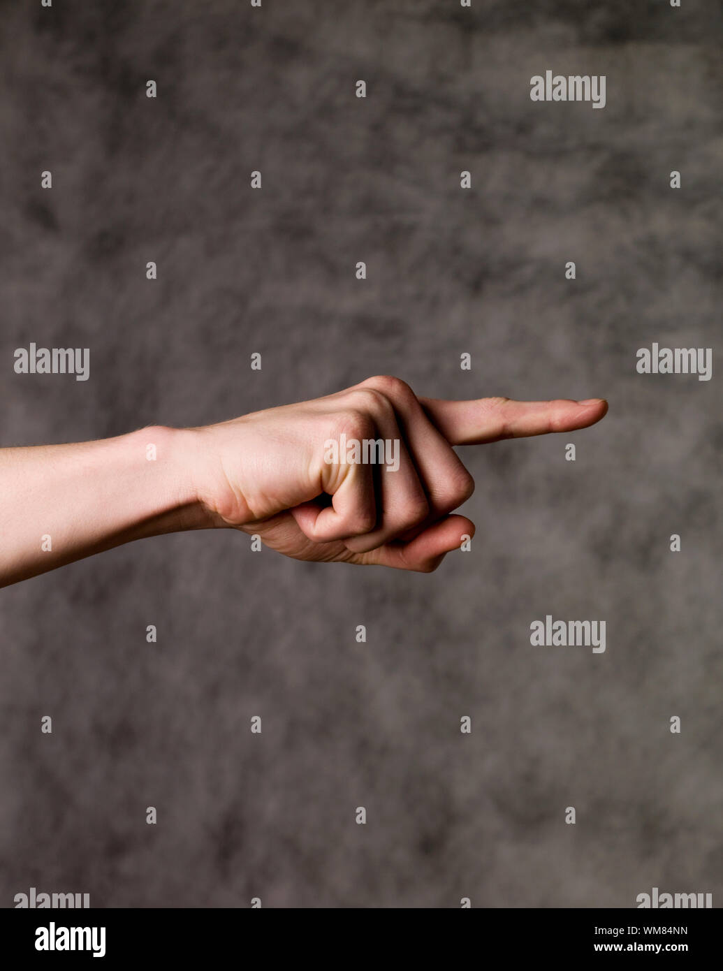Pointing finger towards grey background Stock Photo - Alamy