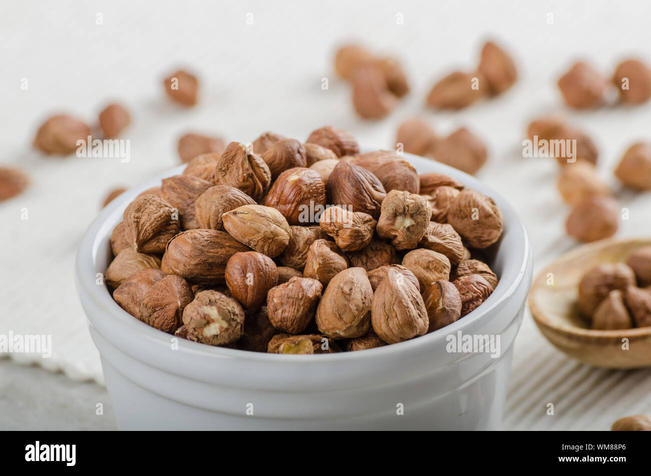 Hazelnuts in a bowl, spoon on the towel, wood, focus on bowl Stock ...