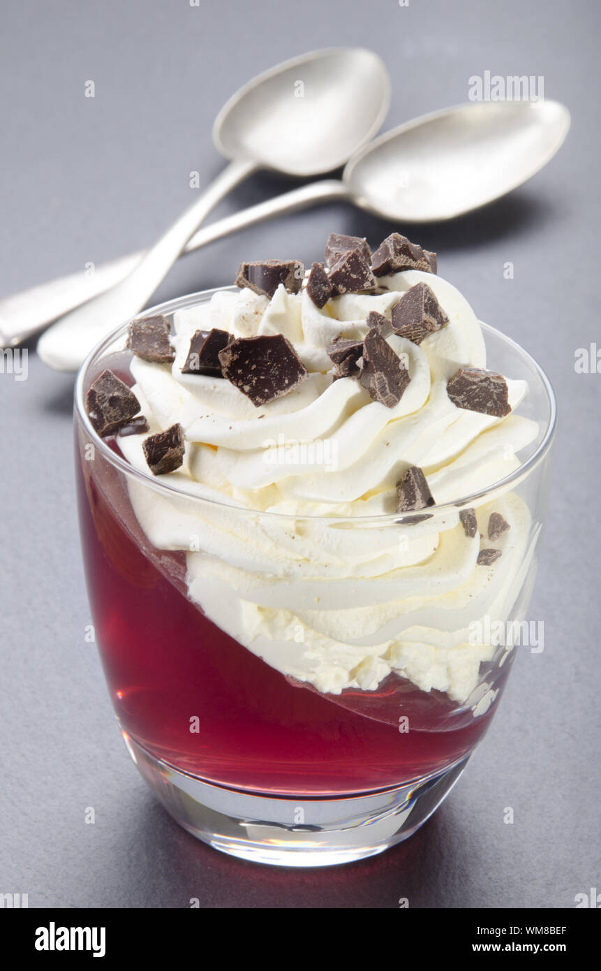 raspberry jelly with whipped cream and broken chocolate in a glass ...