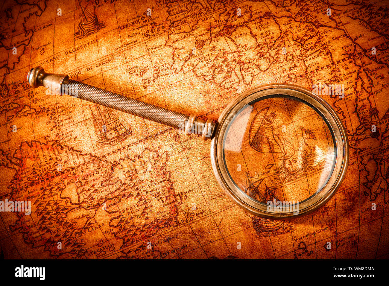Vintage still life. Vintage magnifying glass lies on an ancient world ...