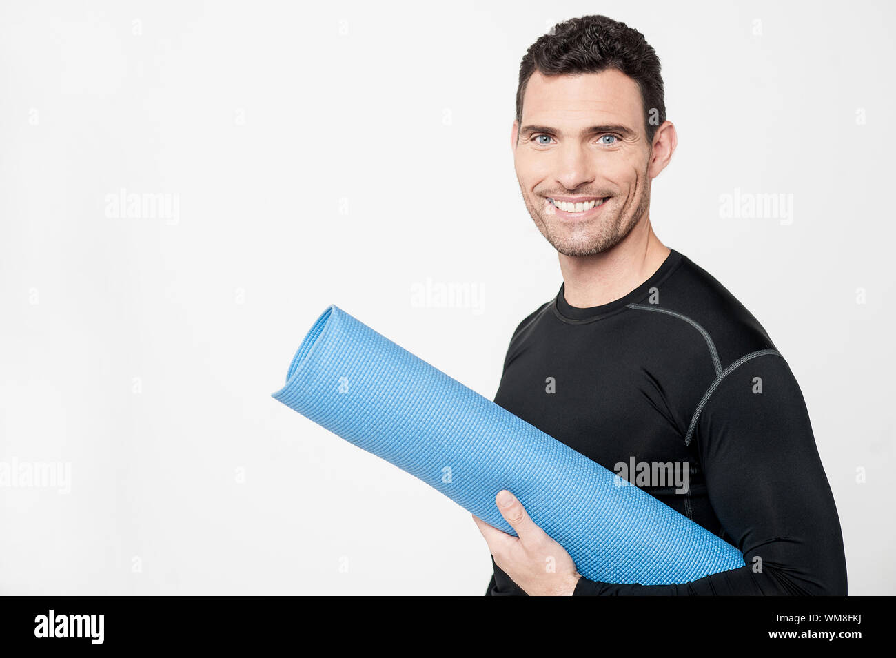 Fitness male with rolled up exercise mat Stock Photo - Alamy