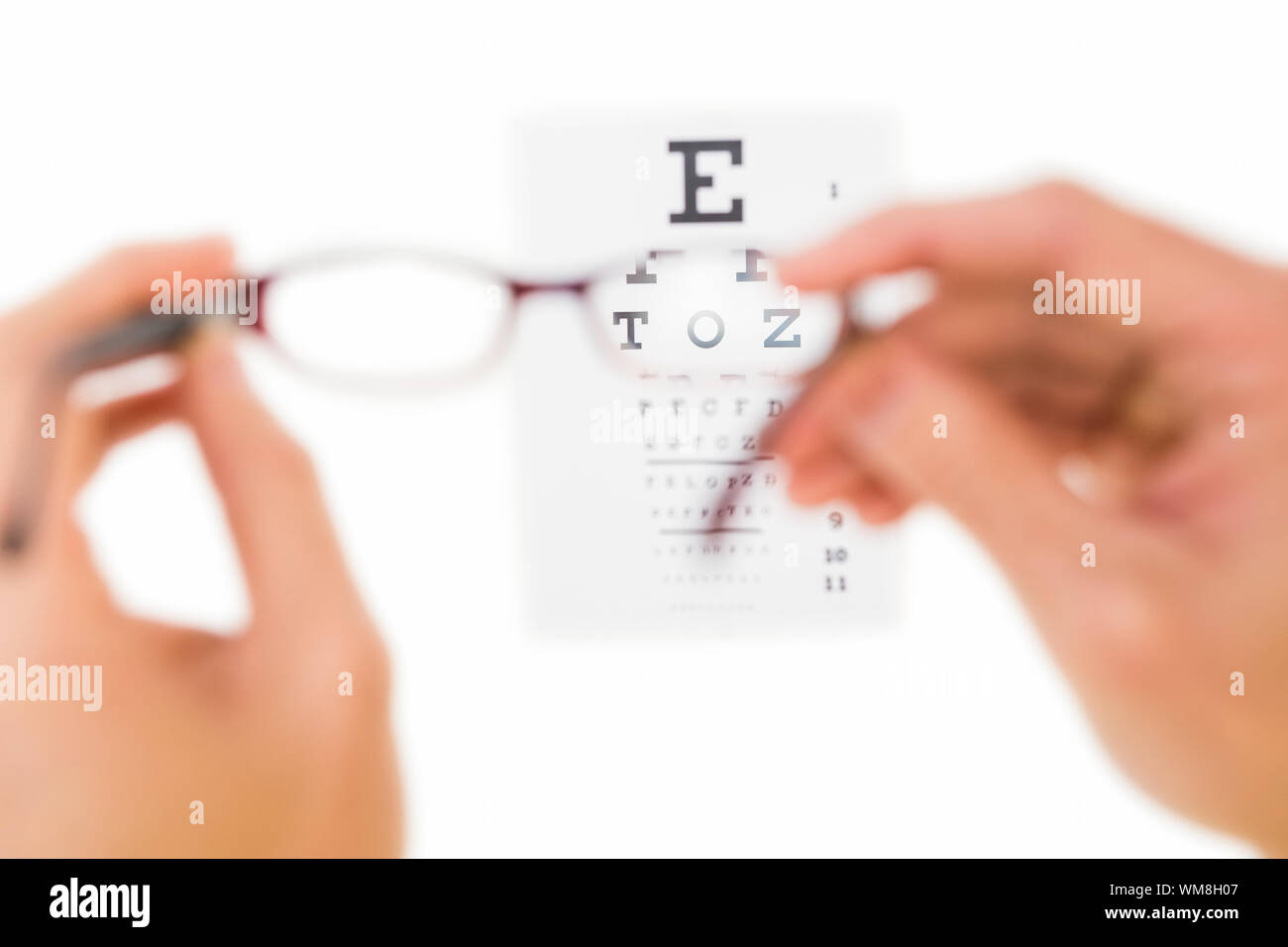 Glasses held up to read eye test on white background Stock Photo - Alamy