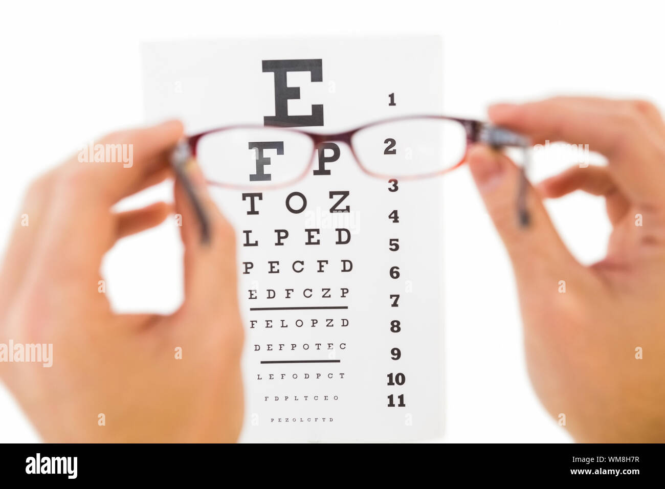 Glasses held up to read eye test on white background Stock Photo - Alamy