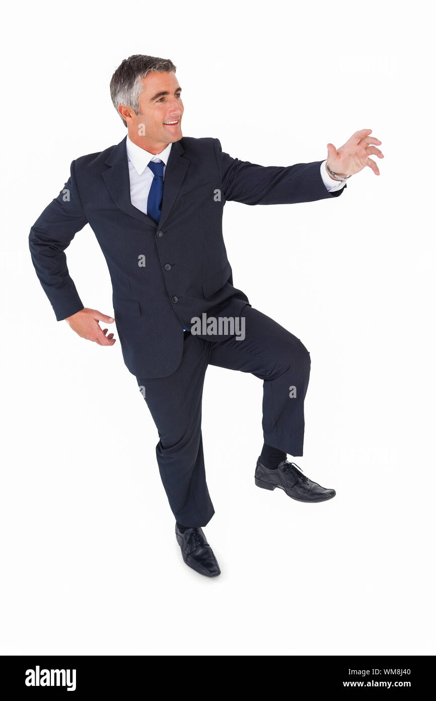 Businessman posing with one foot on floor and arms out on white ...