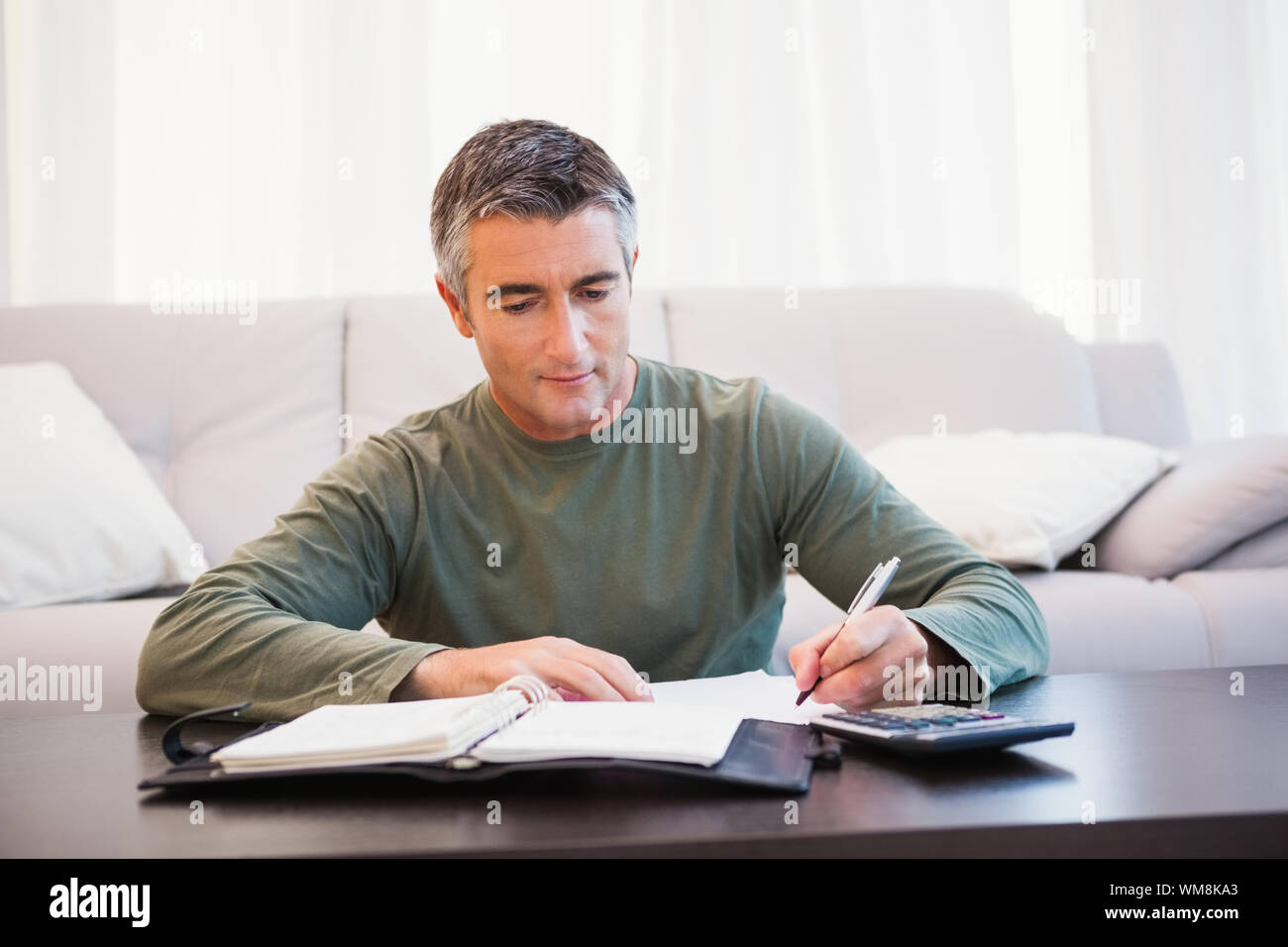 Man taking notes with calculator and notepad on the table at home in ...