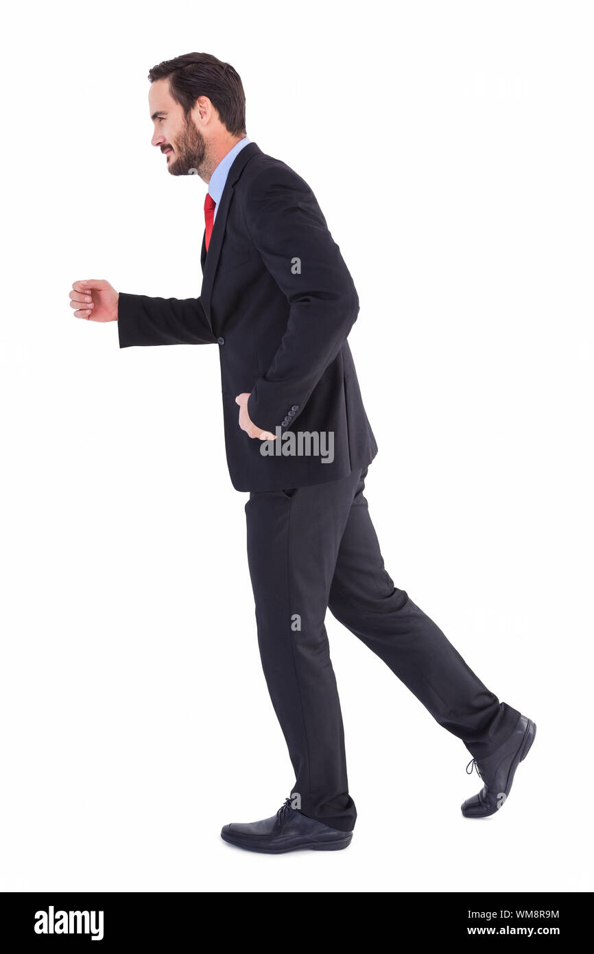Smiling businessman stepping with hands raised on white background ...