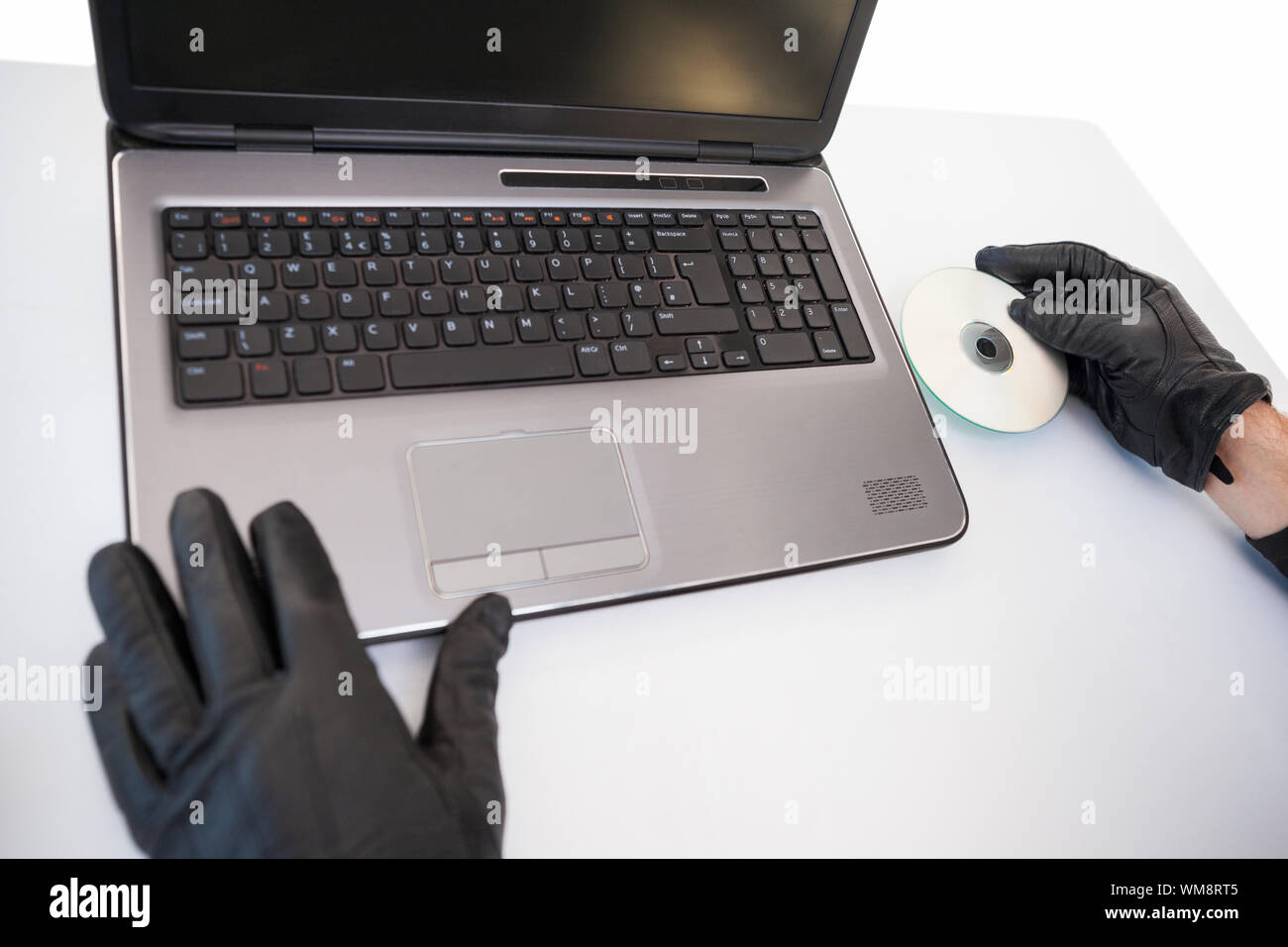 Burglar hacking and putting a cd-rom in laptop on white background ...