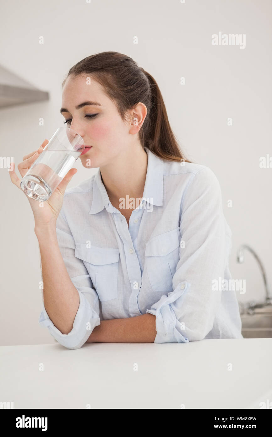 Pretty brunette drinking glass of water at home in the kitchen Stock ...