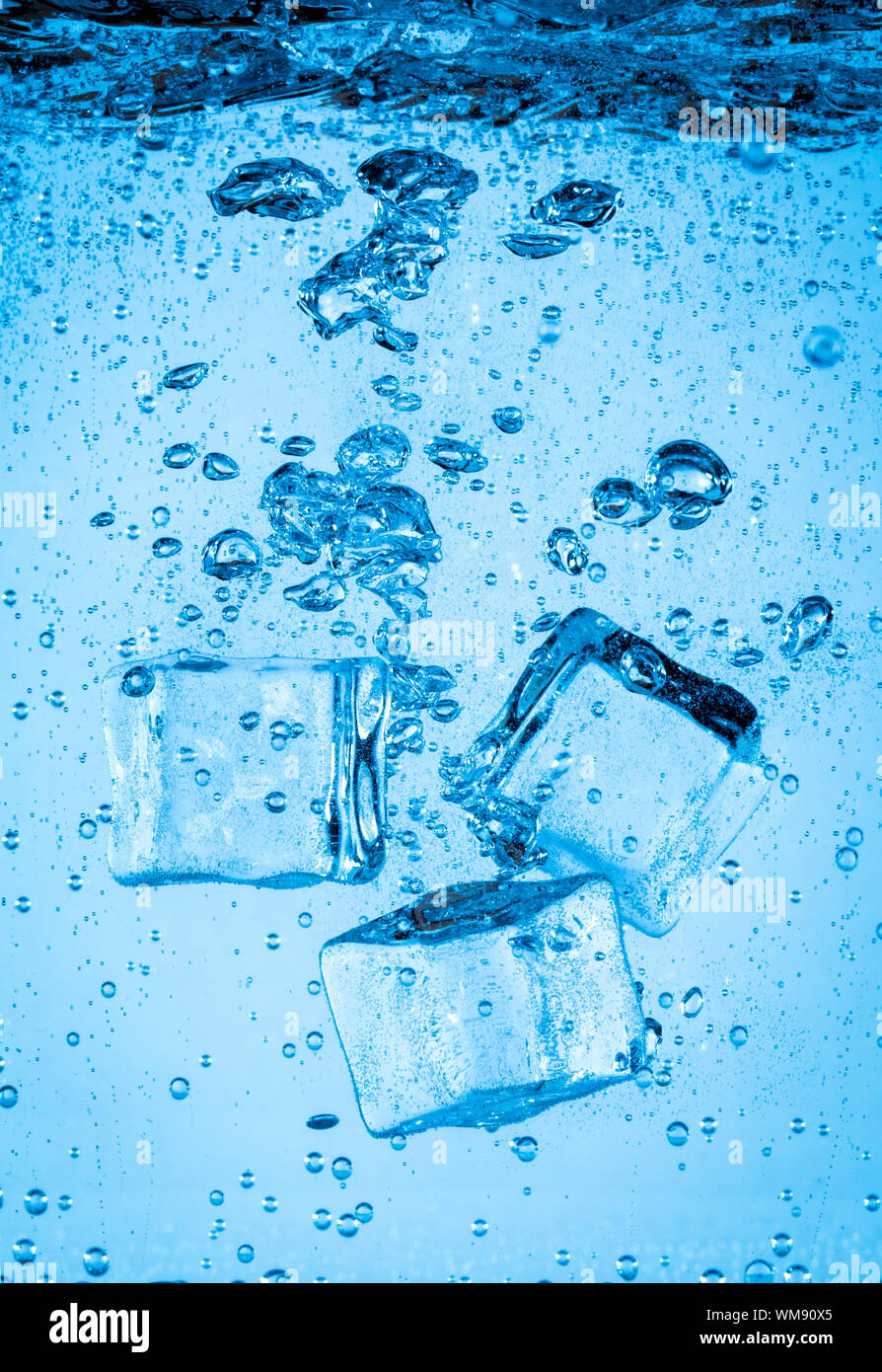 Ice cubes falling into the water sinking to the bottom. Abstract ...