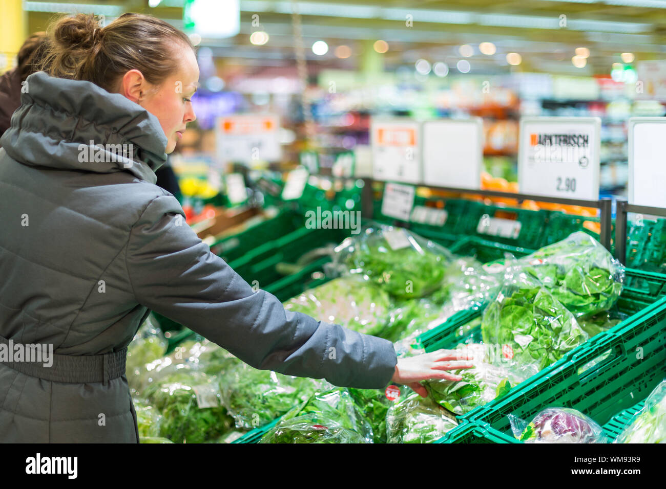 Beautiful, young woman shopping for fruits and vegetables in produce ...