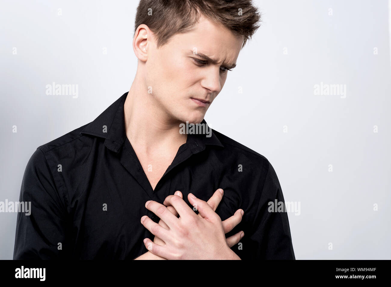 Young man holding his chest with pain Stock Photo - Alamy