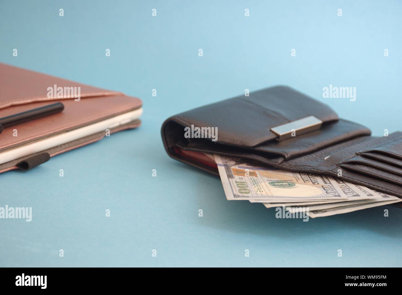 Black wallet with dollar banknotes and tablet against the blue ...