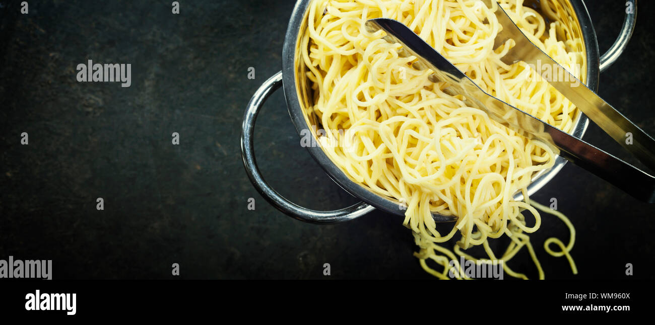 spaghetti in colander on dark vintage background Stock Photo - Alamy