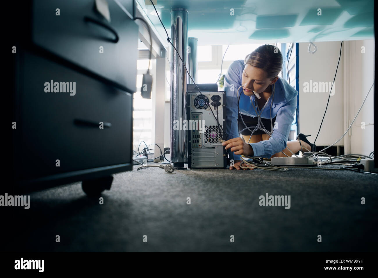 Female assistant working in office, plugging cables to computer and ...