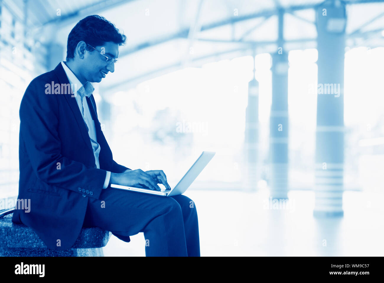 Asian Indian businessman using laptop computer while waiting train at ...