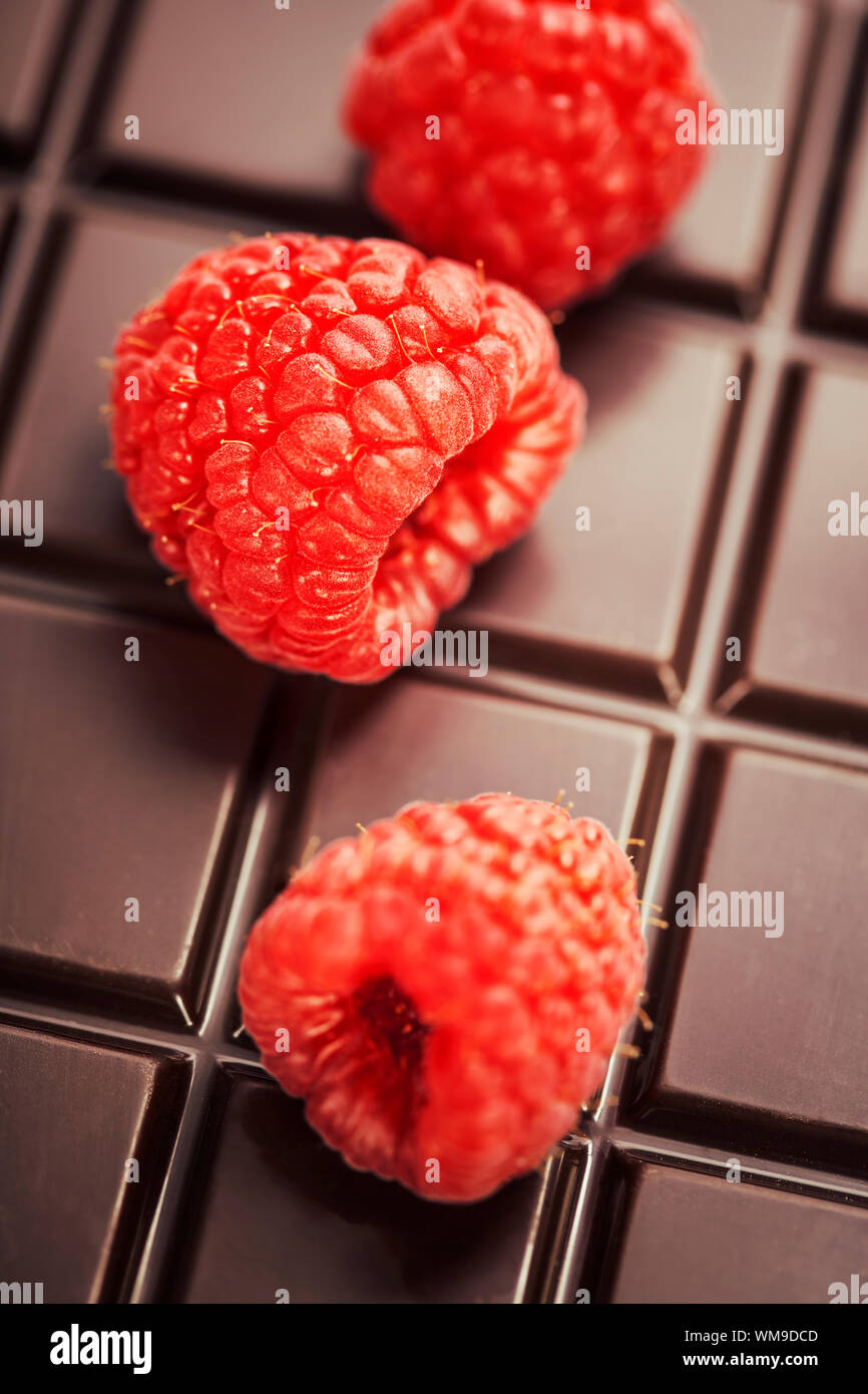 dark chocolate bar with raspberry as background Stock Photo - Alamy