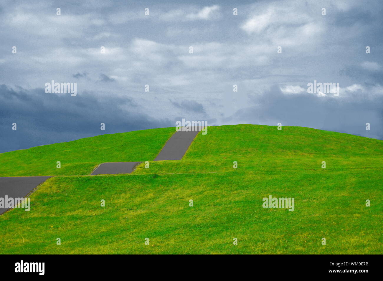 colorful grassland in summer under cloudy sky with path up the hill ...