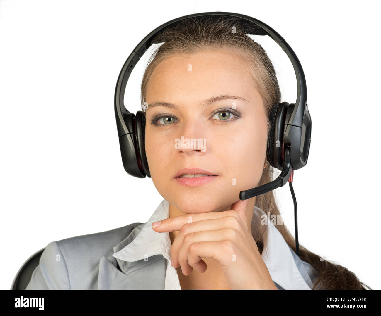 Businesswoman in headset sitting on chair, hand under chin, lips parted ...
