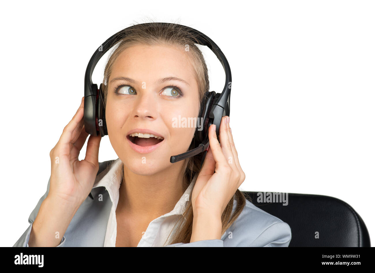 Businesswoman in headset with her hands on headset speakers, looking ...