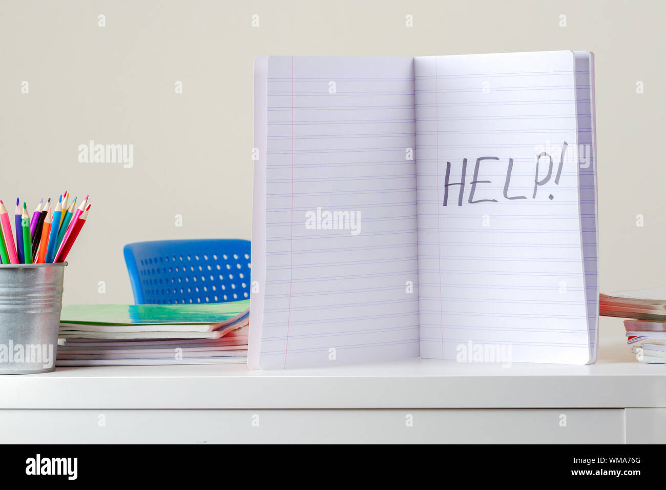 Help sign. Open notebook with written word Help on desk with pile books ...